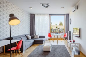 Uma sala de estar moderna com um sofá seccional, uma mesa de jantar com cadeiras, um abajur de chão e uma janela grande com cortinas.