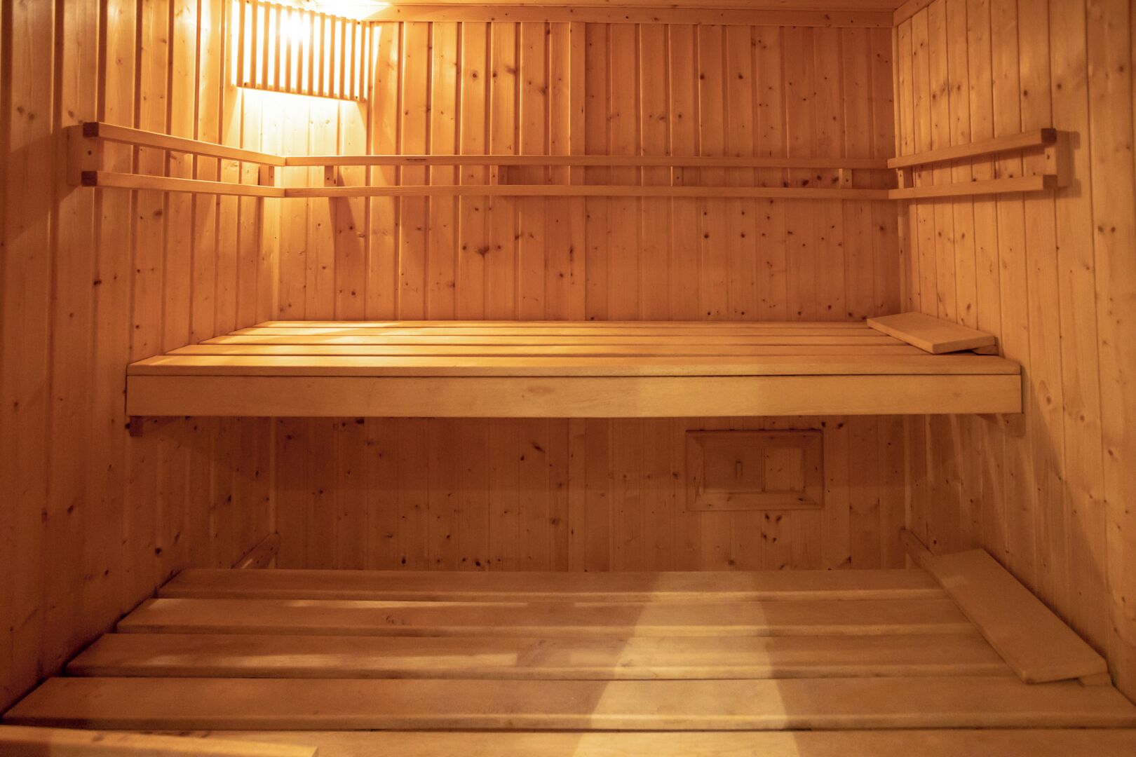 Uma sauna com interior de madeira, um banco e assento.