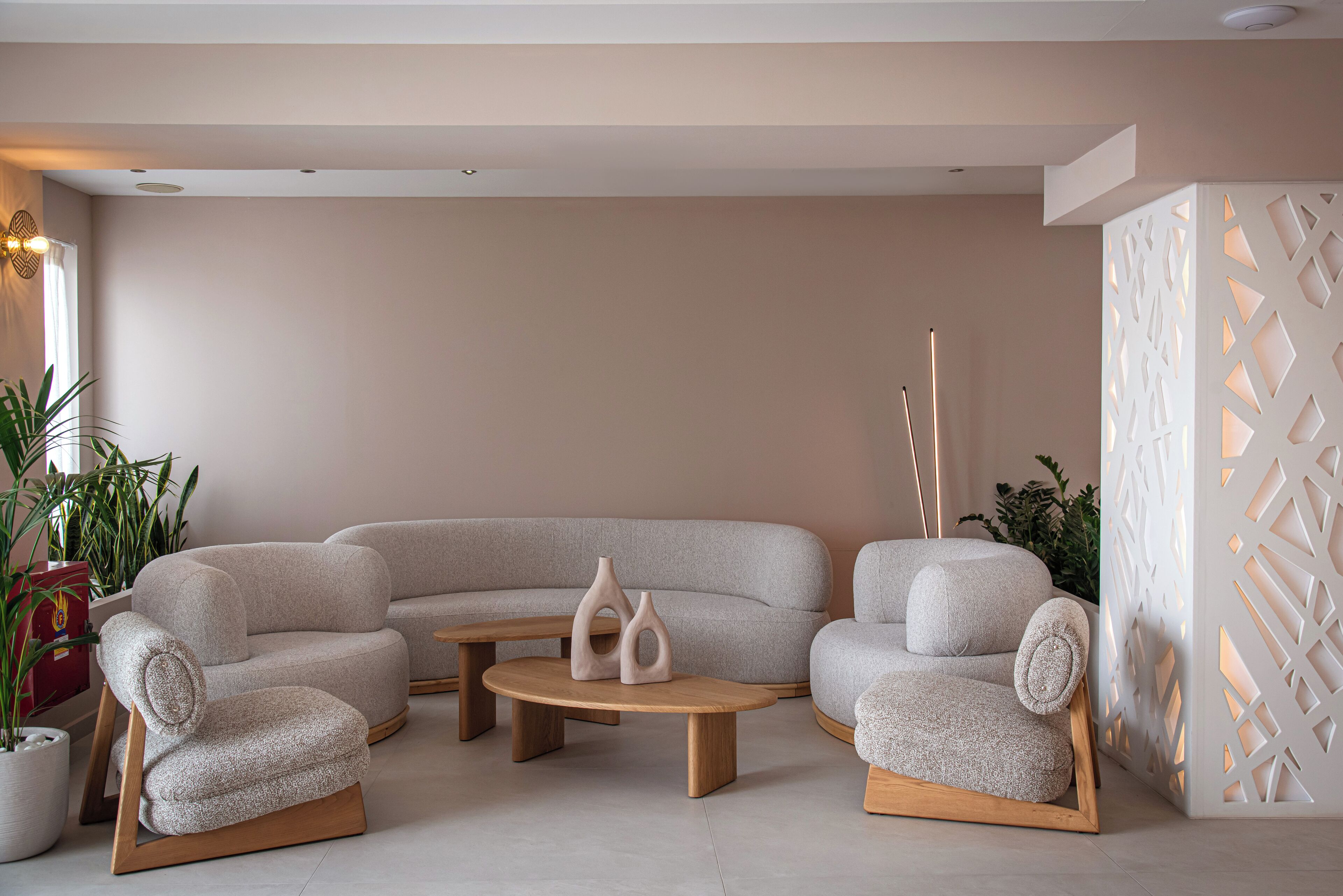 Uma sala de estar moderna com um sofá seccional, duas poltronas, uma mesa de centro e vasos decorativos.