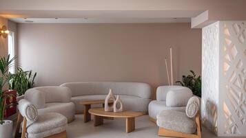 Uma sala de estar moderna com um sofá seccional, duas poltronas, uma mesa de centro e vasos decorativos.
