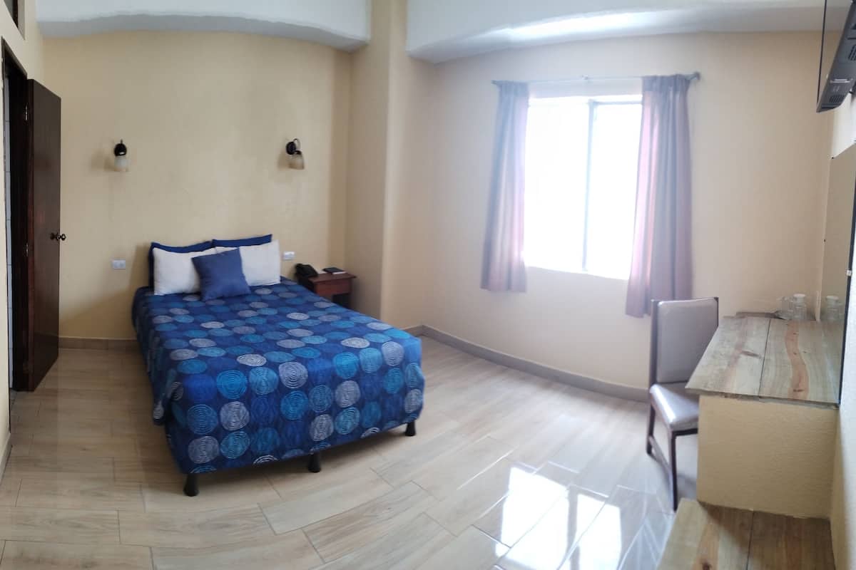 Quarto com cama, escrivaninha e janela.