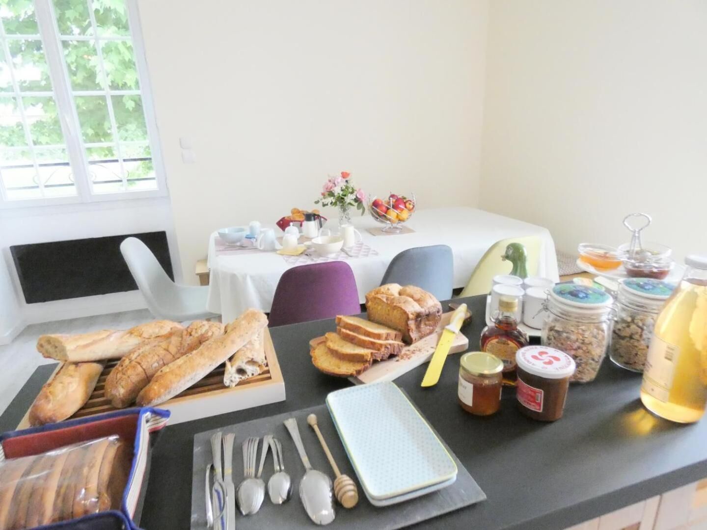 Uma mesa posta para o pequeno-almoço, com pão, manteiga, compotas e mel.