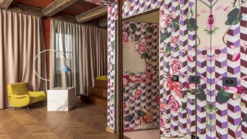 Quarto moderno com parede estampada em padrão geométrico, uma cadeira amarela, uma mesa de mármore branco e piso de madeira.