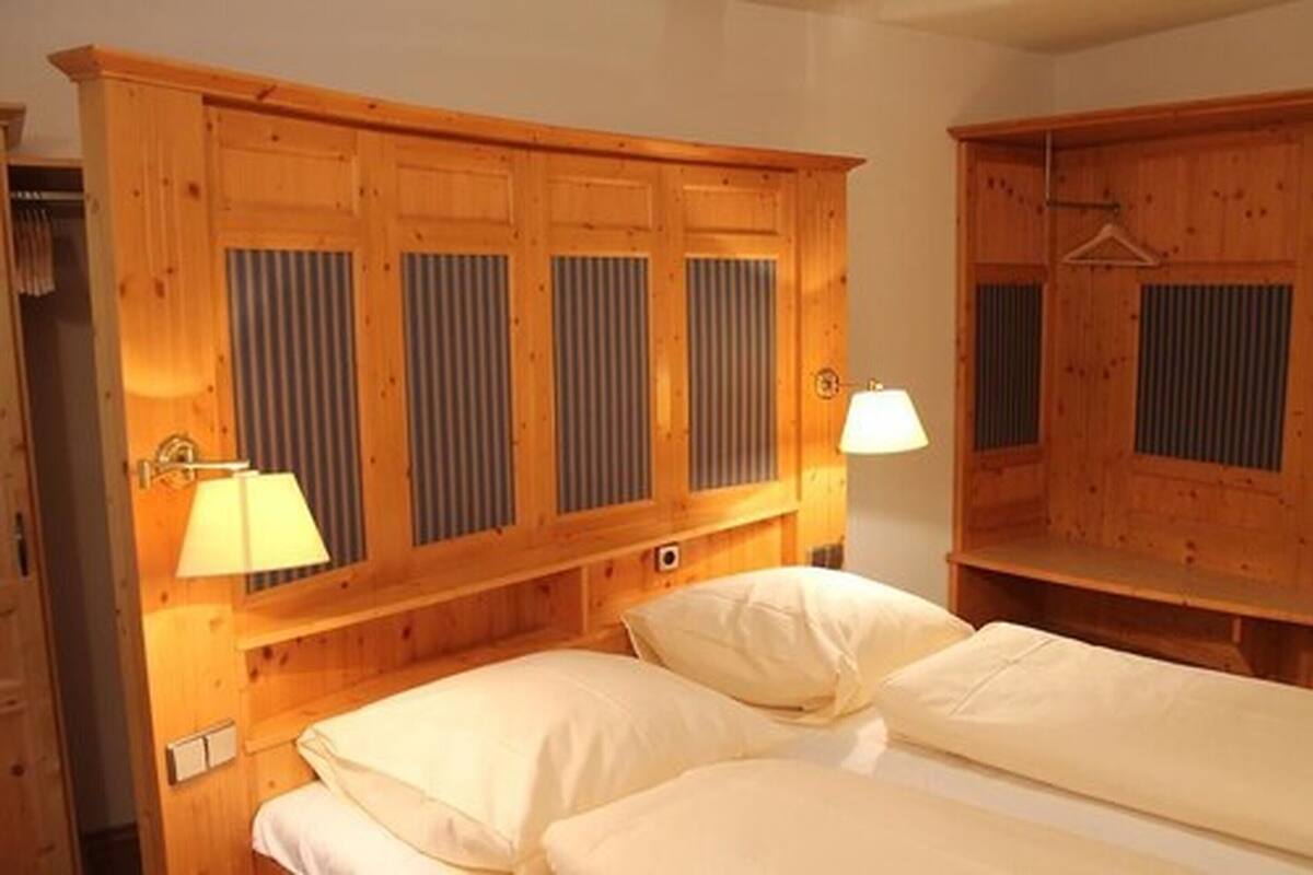 Quarto com beliche de madeira, cabeceira de madeira e duas luminárias de cabeceira.