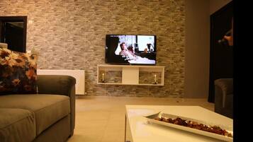 Uma sala de estar com parede de tijolos, televisão de tela plana, sofá e mesa de centro.