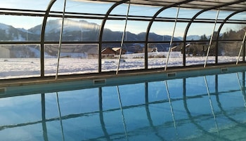 Piscina interna com vista para montanhas nevadas através de grandes janelas.