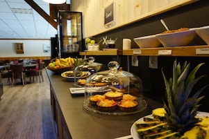 Uma área de buffet com diversos alimentos e um arranjo de frutas tropicais.