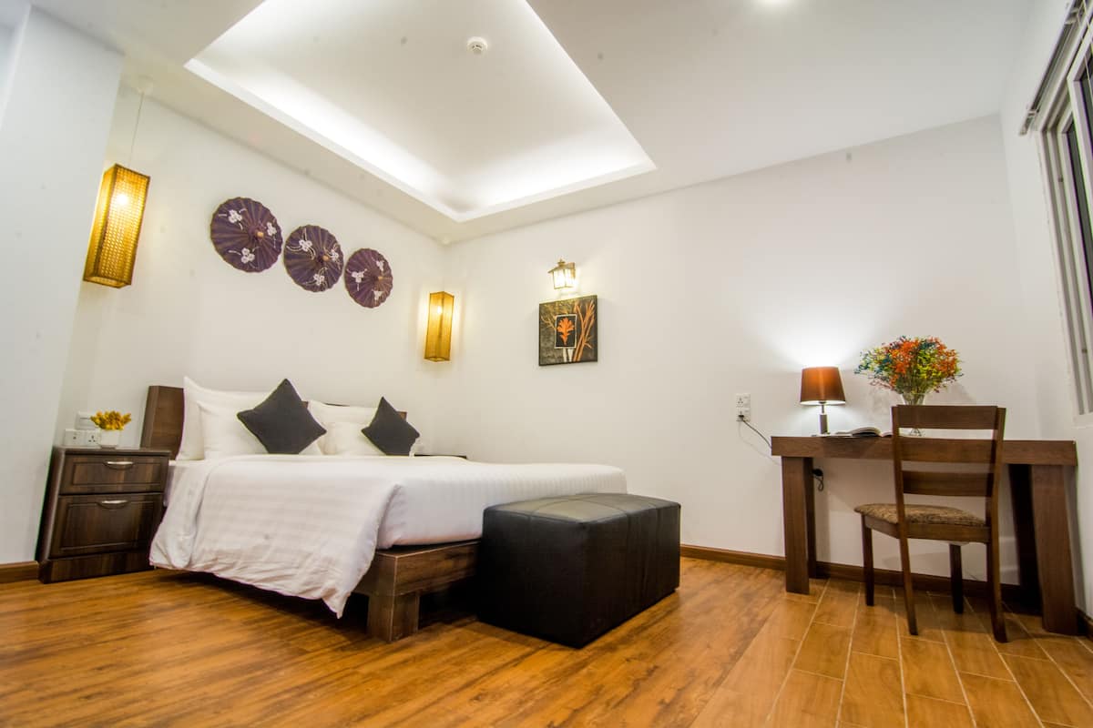 Quarto com cama, mesas de cabeceira, escrivaninha e cadeira, e luminária no teto.