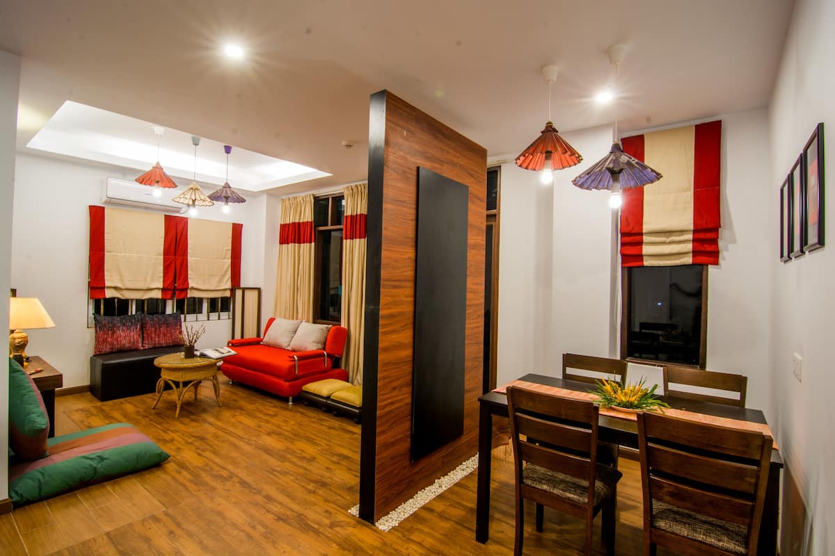 Uma sala de estar moderna com um sofá vermelho, uma mesa de jantar de madeira e uma janela grande com cortinas.