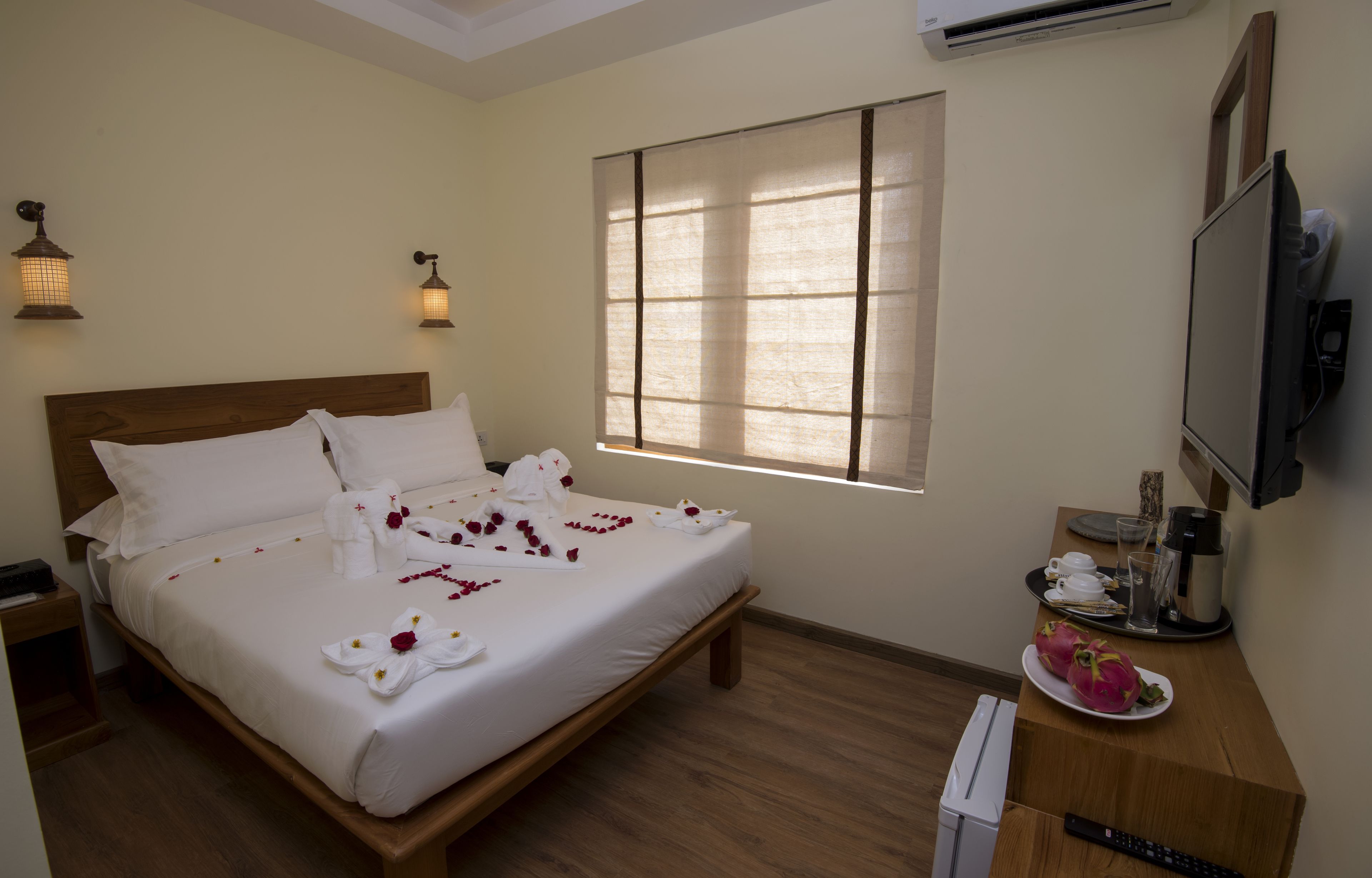 Quarto de hotel com cama, abajures, televisão, máquina de café e arrumação para o pequeno-almoço.