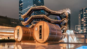 Uma estrutura arquitetônica moderna com barris de madeira rotulados 'Equinox' e fachada de vidro.