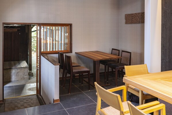 Um quarto tradicional japonês, com piso de tatame, uma mesa de madeira e cadeiras.