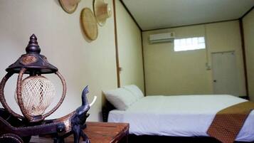 Quarto com uma cama, mesa de cabeceira com abajur decorativo e ar-condicionado fixado na parede.