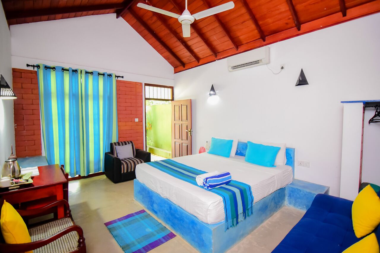Quarto com cama, escrivaninha, cadeira e ventilador de teto.
