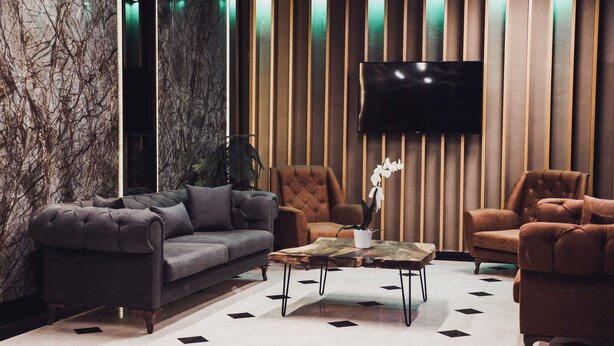 Uma sala de estar moderna com sofá, poltronas, mesa de centro e TV fixada em uma parede de madeira.