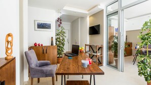 Uma sala de jantar moderna com mesa de madeira, um laptop e uma planta em vaso.