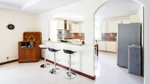Uma cozinha moderna com ilha central, banquetas, armário de madeira e geladeira.
