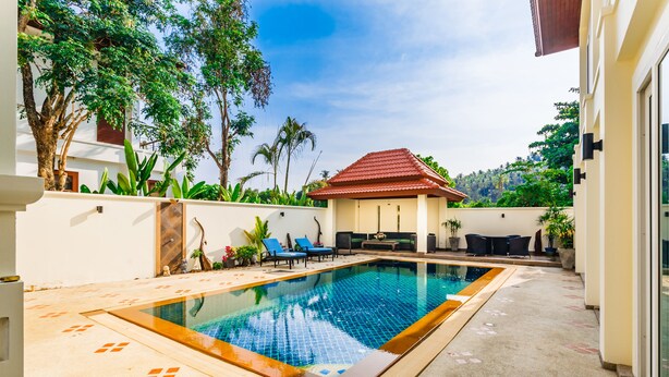 Uma piscina com espreguiçadeiras e um pequeno edifício com telhado vermelho.