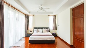 Um quarto espaçoso com uma cama grande, ventoinha no teto e piso de madeira.