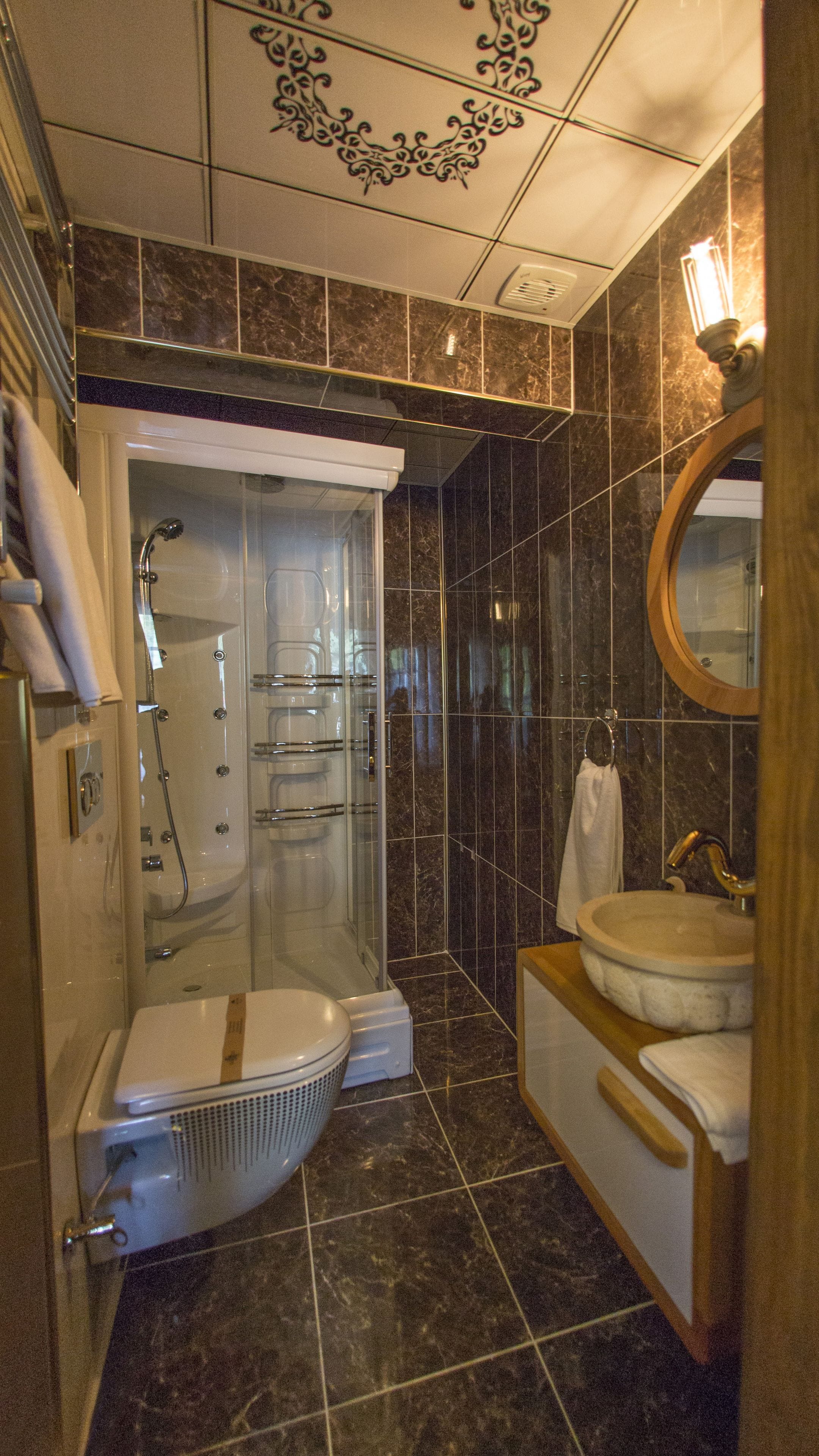 Uma casa de banho moderna com cabine de duche em vidro, sanita branca e toucador de madeira com lavatório.