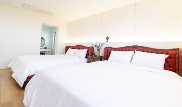 Quarto de hotel com duas camas, um aparador e um espelho.
