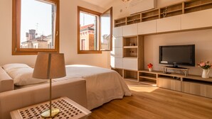 Quarto moderno com cama, luminária de cabeceira, televisão e estantes embutidas.
