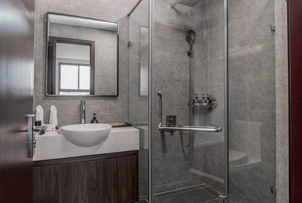 Uma casa de banho moderna com chuveiro de vidro, lavatório branco e um espelho grande sobre a toucador.
