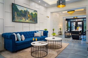 Uma sala de estar moderna com um sofá azul, duas mesinhas de centro redondas e um quadro na parede.