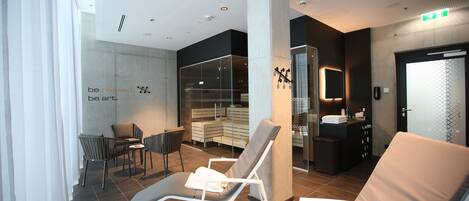 Um saguão de hotel moderno com poltronas de descanso, um balcão de recepção e um banheiro visível.