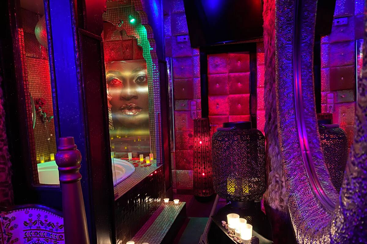 Um quarto com parede espelhada, um banco com velas e um vaso decorativo.
