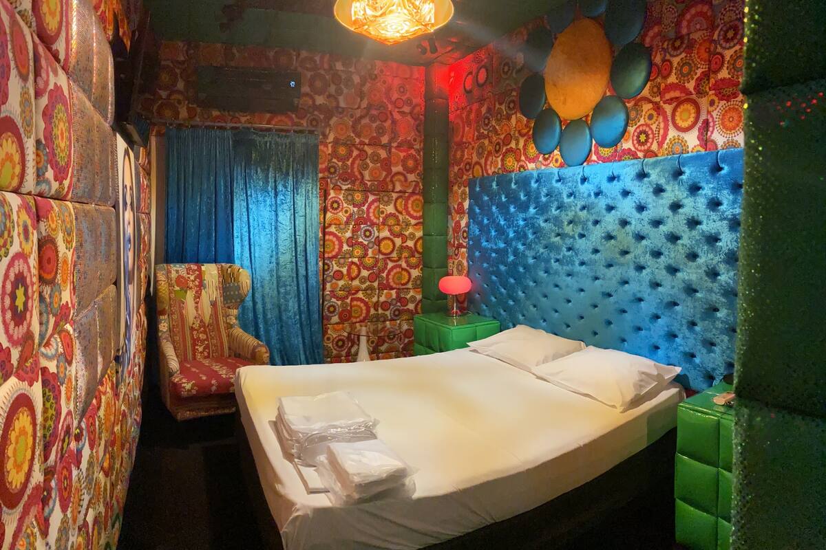 Um quarto com uma cama, uma cadeira e uma parede com um padrão circular.