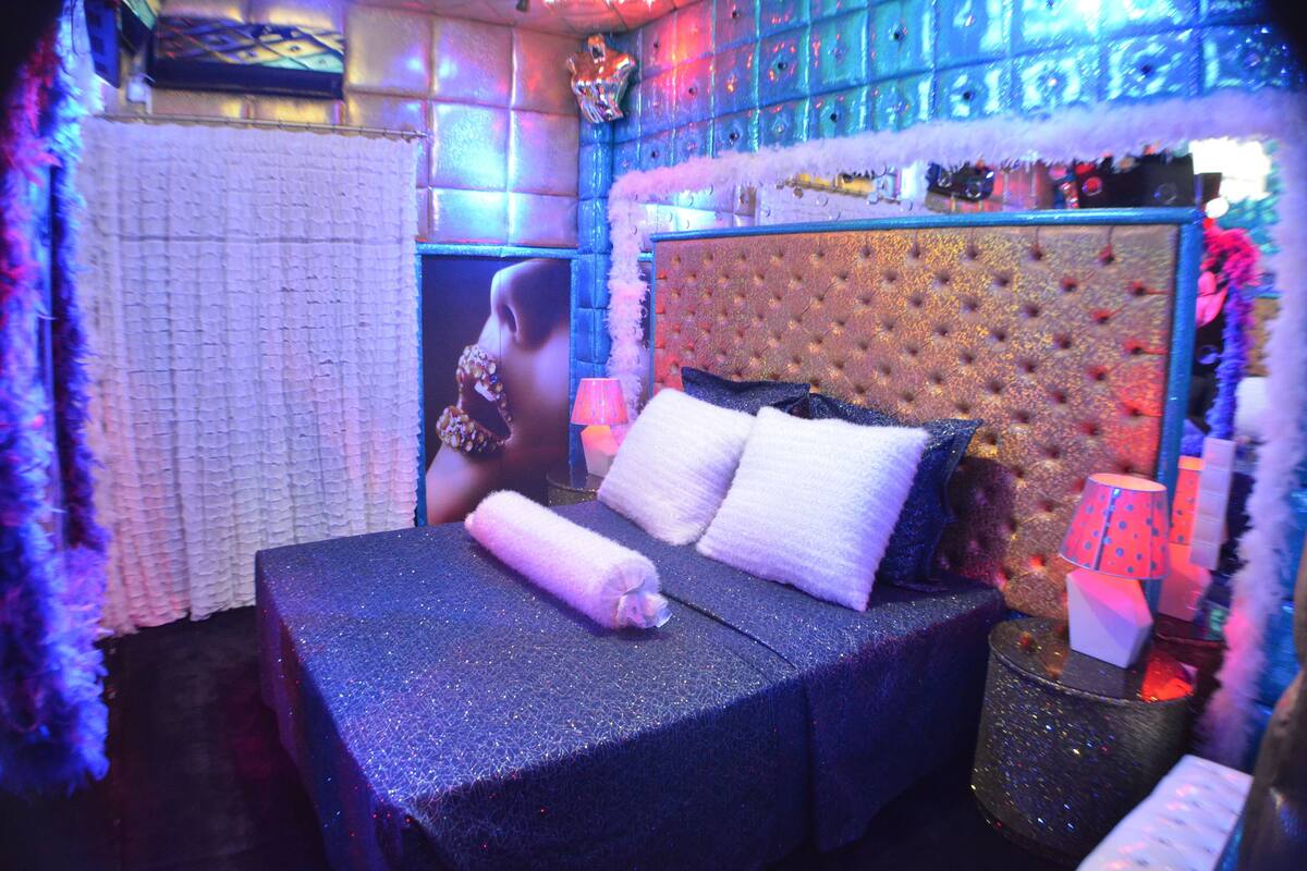 Quarto com cama, almofadas, mesa de cabeceira e decoração na parede.