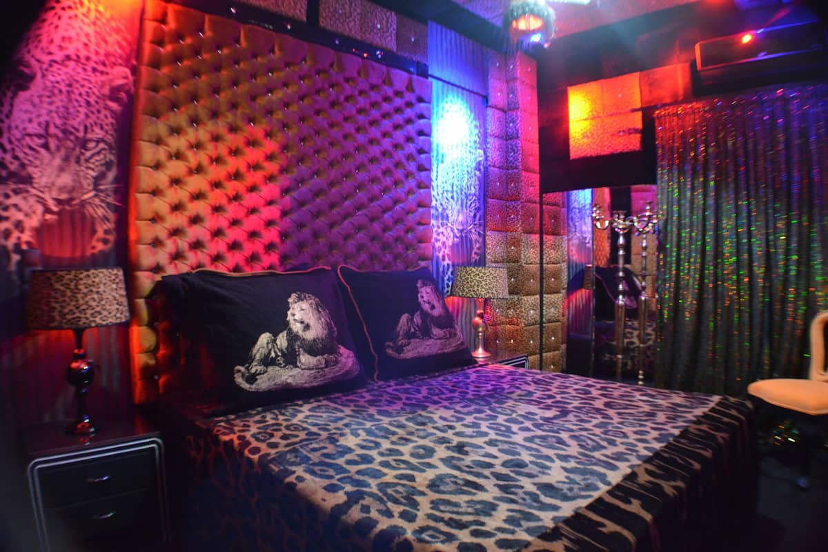 Quarto com cabeceira estofada, colcha de onça e almofadas decorativas.