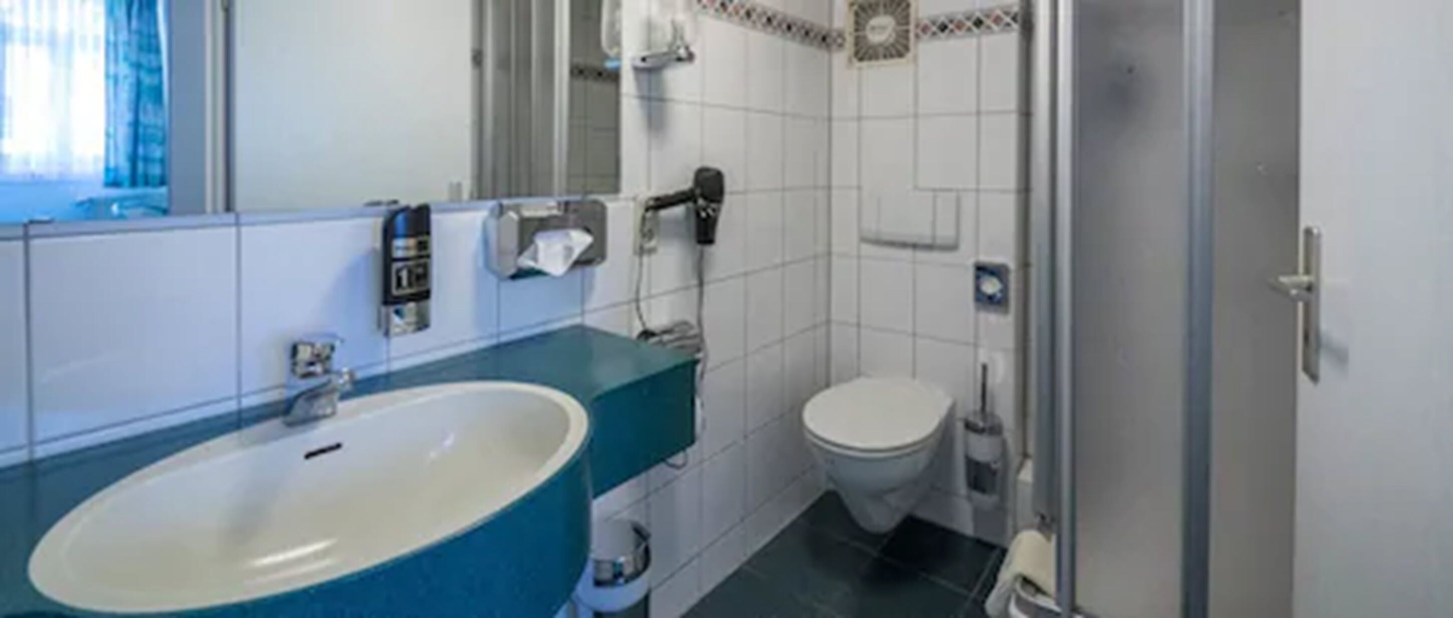 Casa de banho com lavatório, sanita e chuveiro.