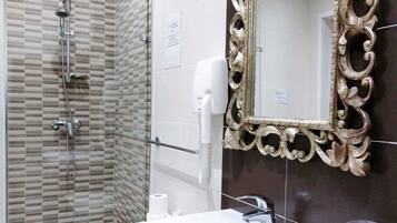 Casa de banho com chuveiro, pia e espelho decorativo.