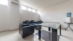 Uma sala de estar moderna com mesa de centro de vidro, sofás pretos e um sistema de ar condicionado embutido.