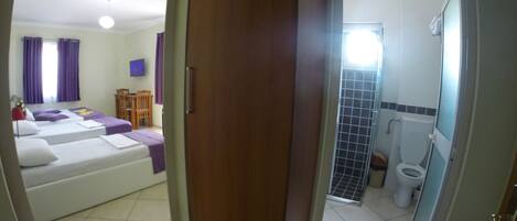 Quarto com duas camas, banheiro e chuveiro.