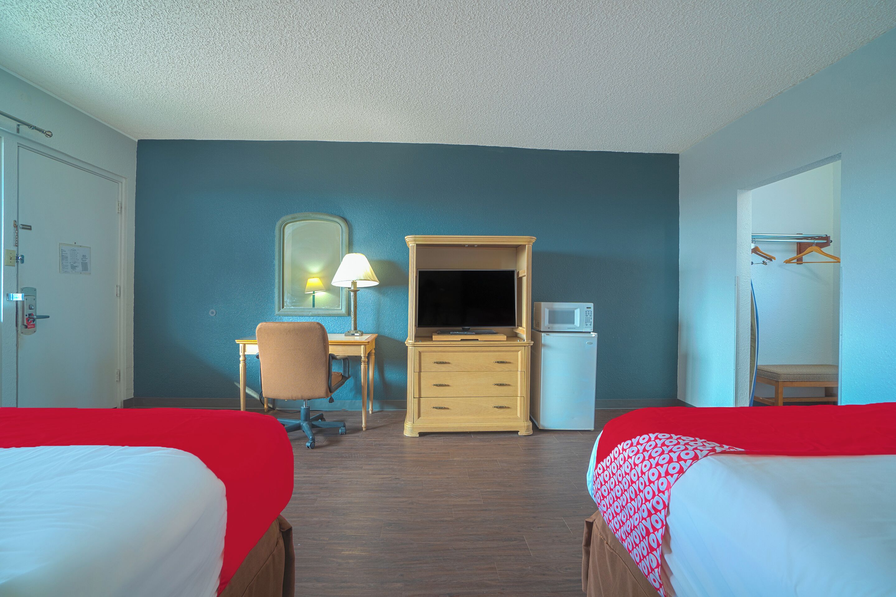 Quarto de hotel com duas camas, uma escrivaninha com cadeira, televisão, micro-ondas e um guarda-roupa.