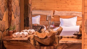 Interior de cabana de madeira com cama, toalhas e pia de madeira.