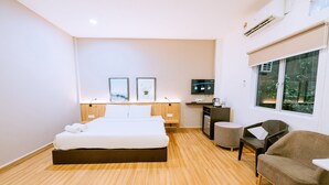 Quarto de hotel moderno com uma cama grande, uma escrivaninha, uma cadeira e uma televisão.