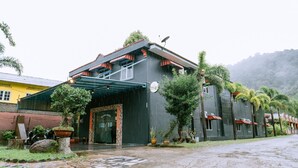 Um edifício com entrada coberta, plantas em vasos e um caminho de pedra que leva à entrada.
