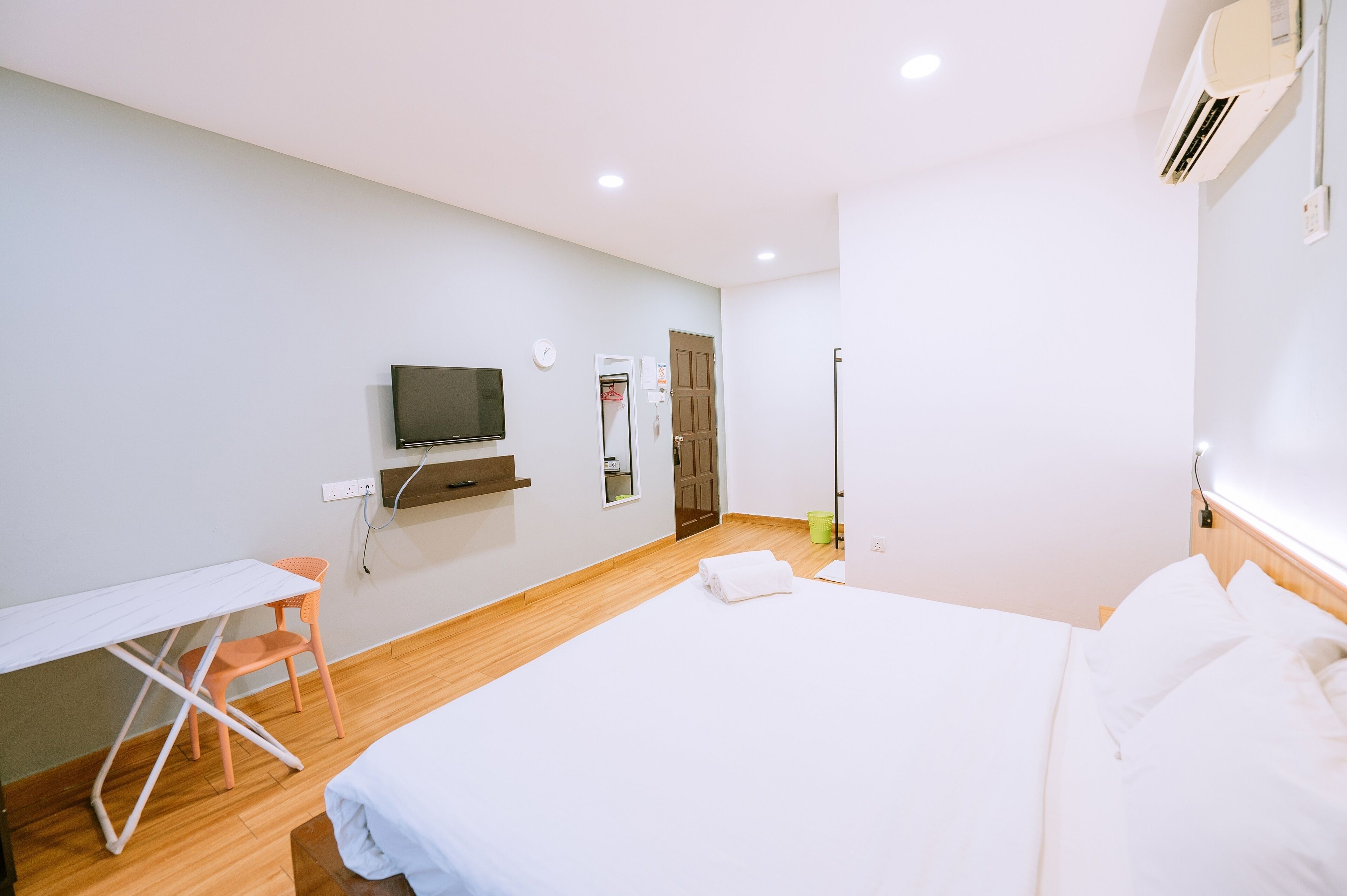 Quarto de hotel moderno com uma cama grande, uma escrivaninha, uma cadeira, uma televisão e um ar condicionado.