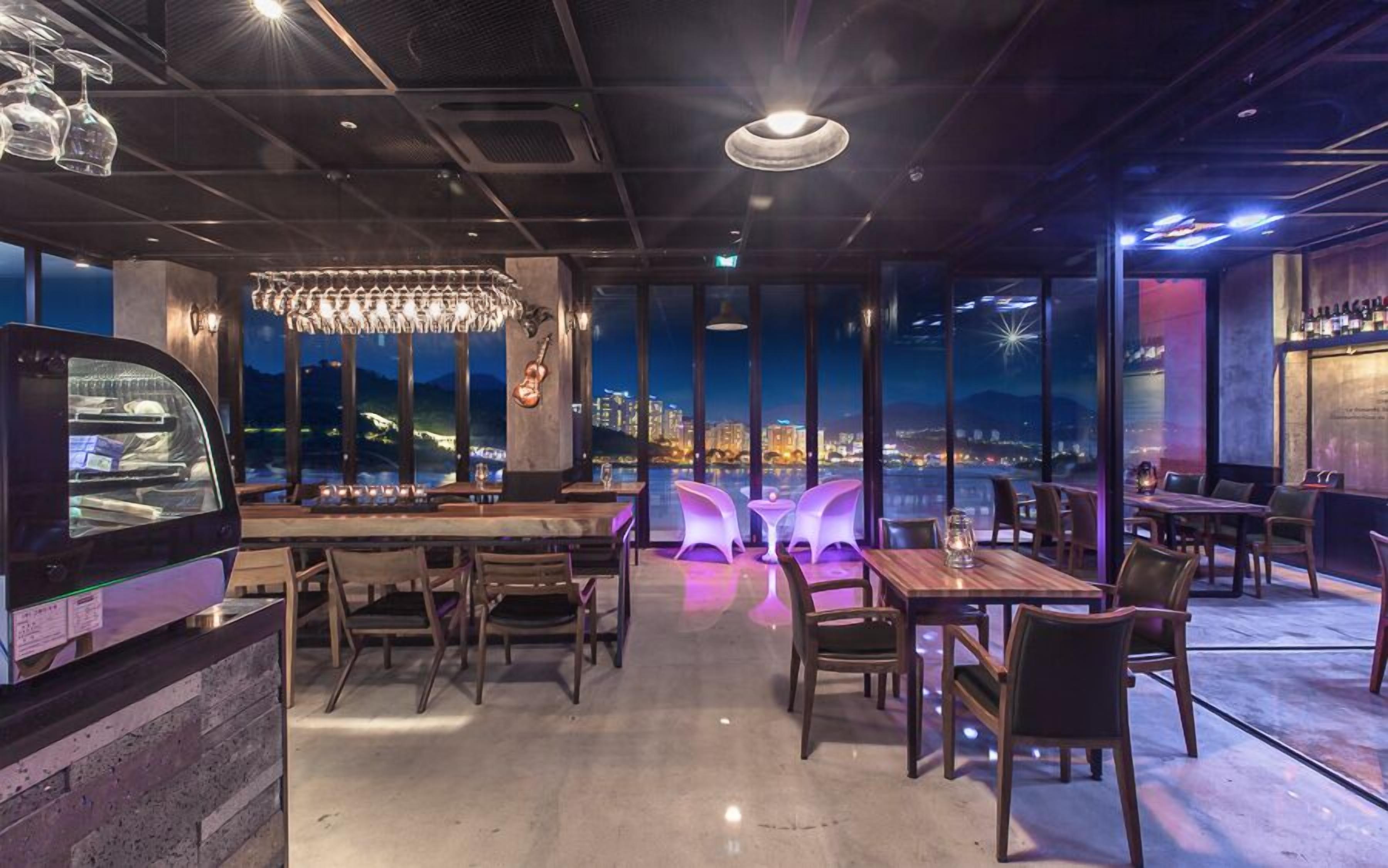 Um restaurante com área de bar, mesas e cadeiras.