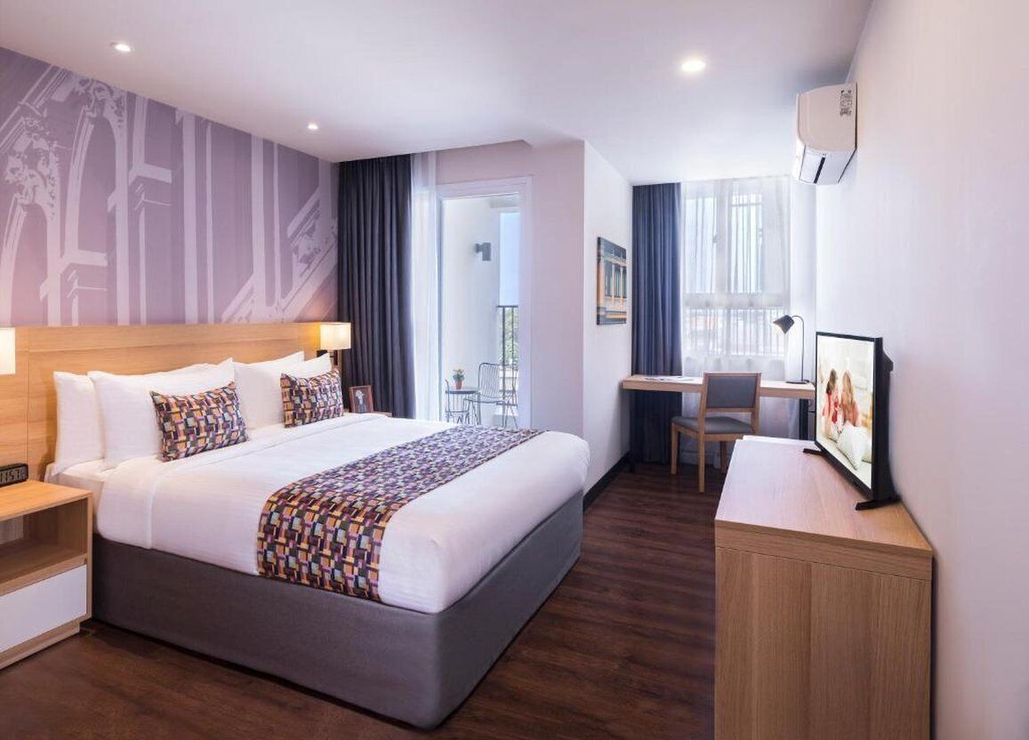 Quarto de hotel moderno com uma cama grande, uma escrivaninha e uma varanda.