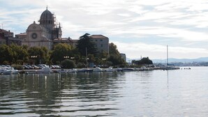 Um cais com barcos atracados, um edifício histórico com cúpula, e um céu claro.