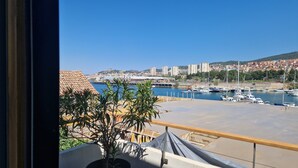 Marina com barcos, céu limpo e edifícios ao fundo.