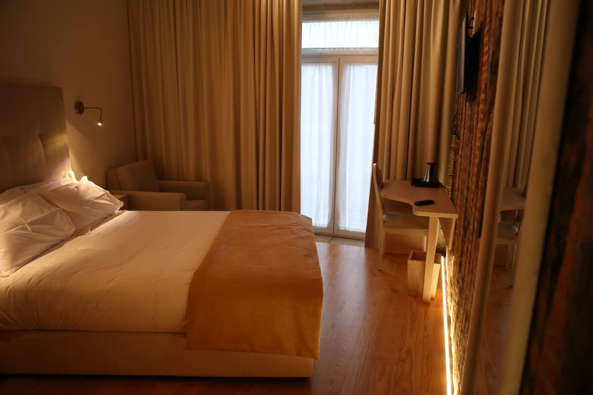Quarto de hotel com uma cama grande, uma mesa e uma cadeira.
