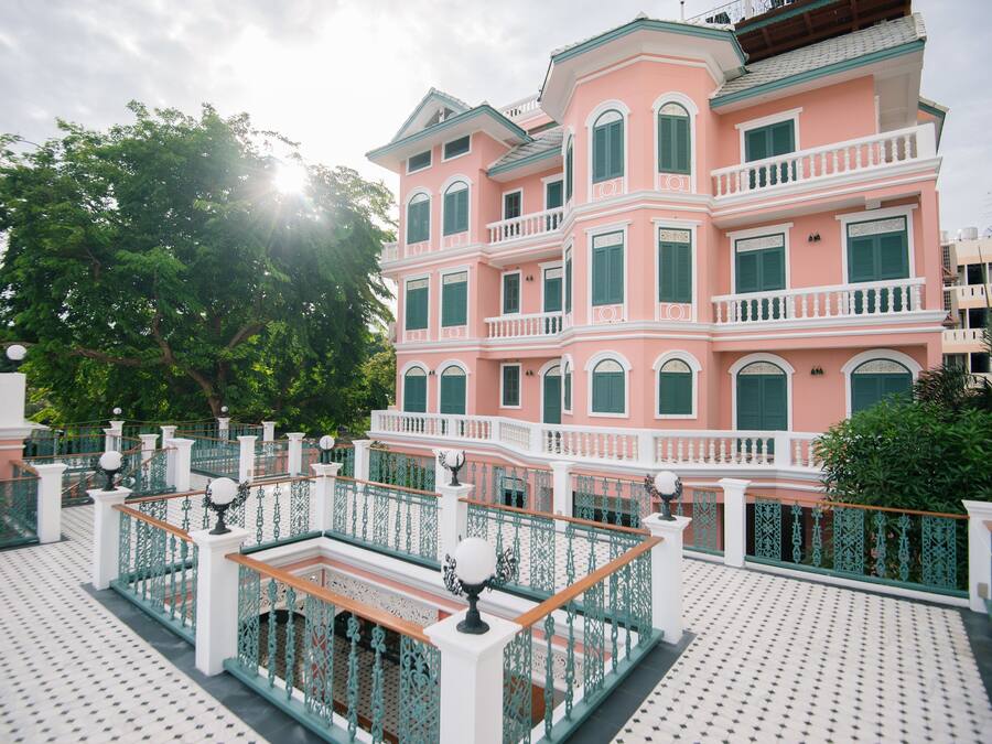 Um edifício rosa com varandas e soalho em azulejos.