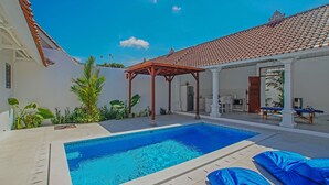 Piscina com pergolado, área de estar externa e telhado cerâmico.