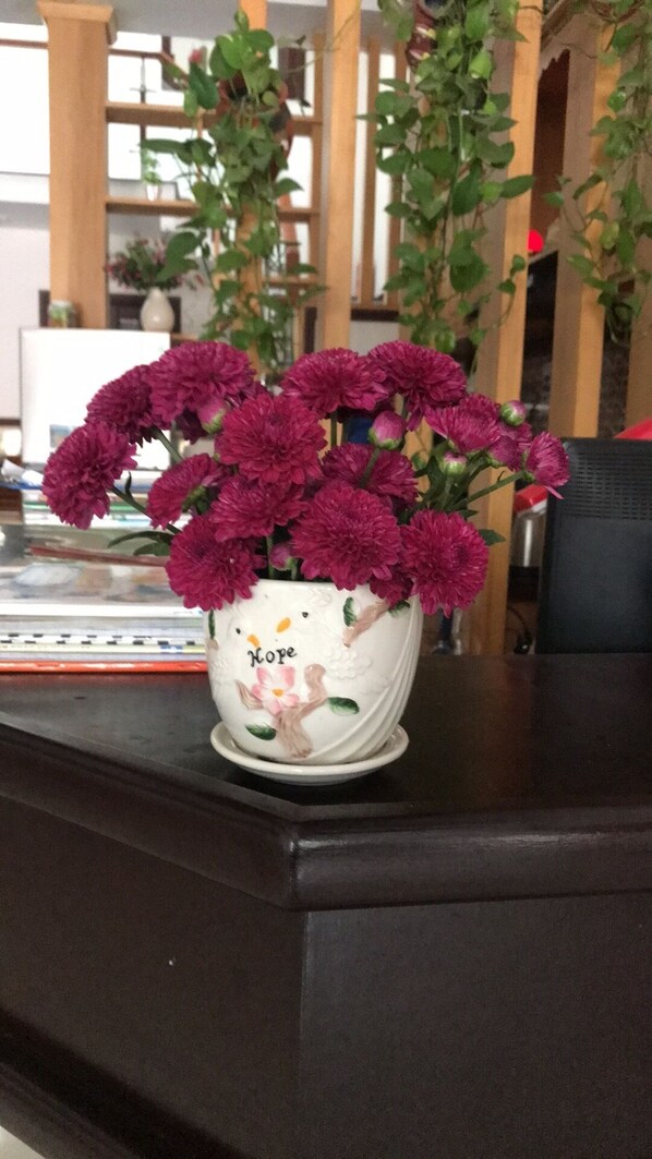 Um vaso de cerâmica branca com a palavra 'Hope' e desenhos florais sobre uma escrivaninha de madeira escura.
